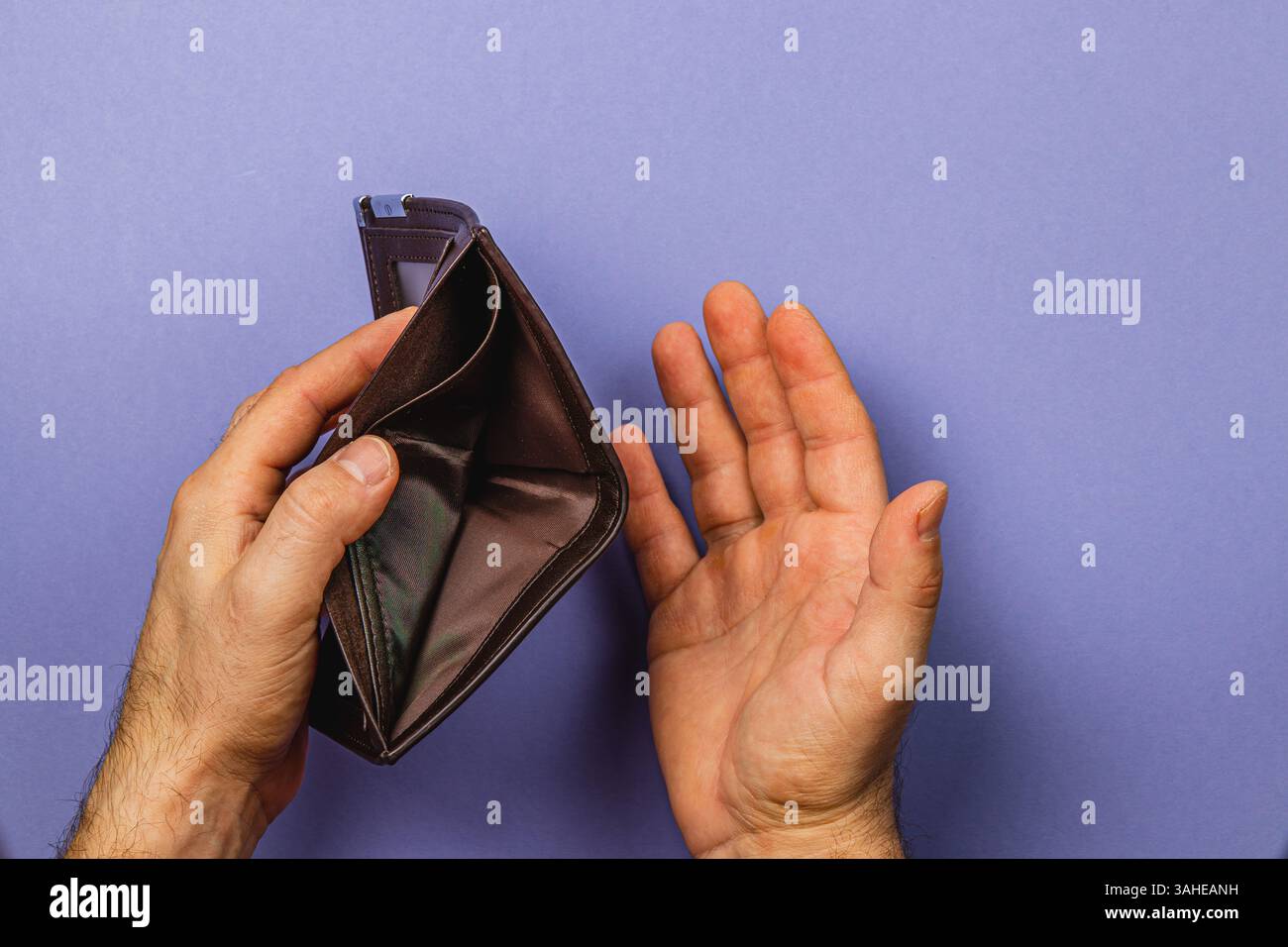 A male businessperson holds an empty leather wallet with an expression ...