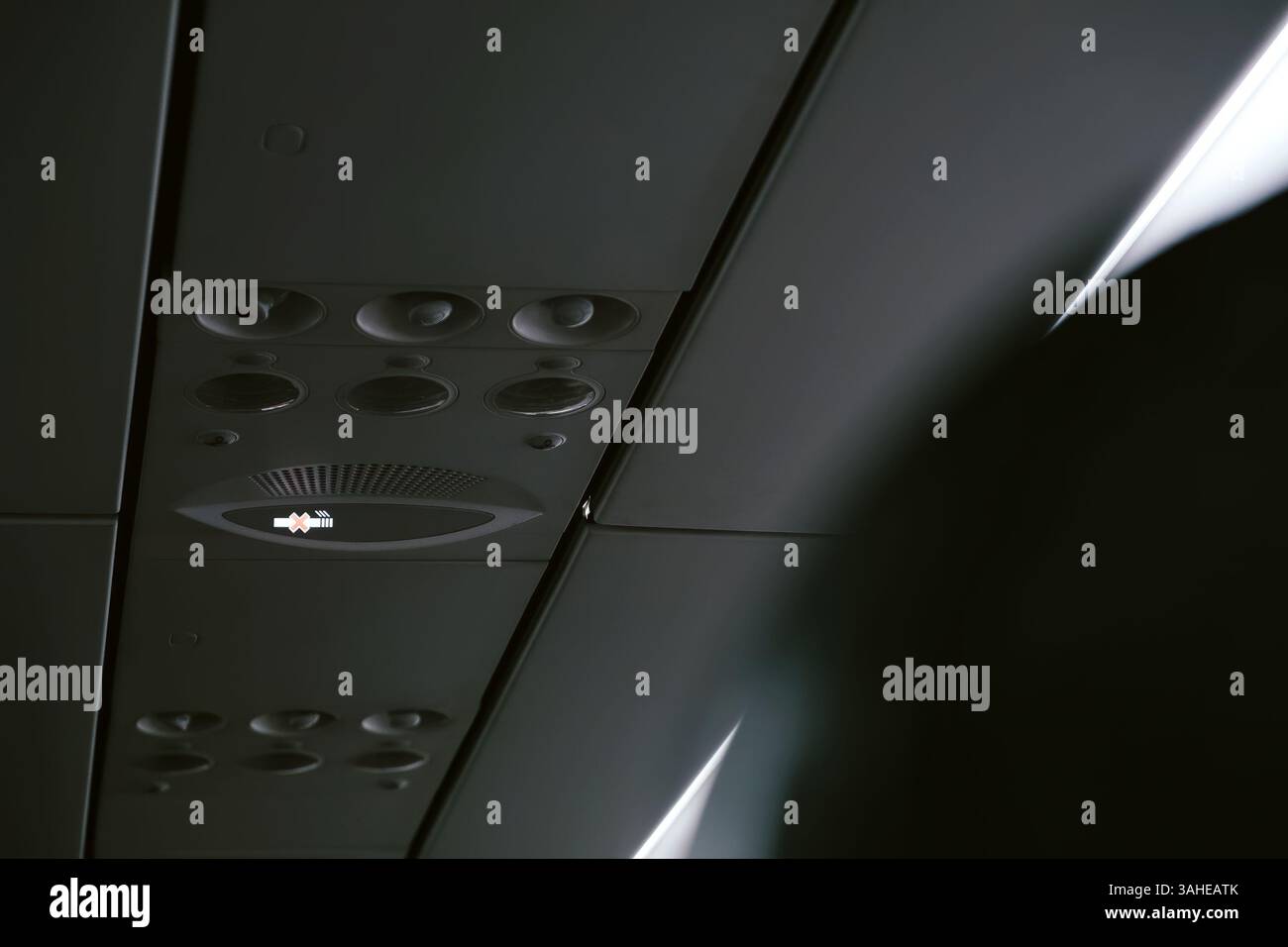 no smoking sign light up on ceiling of airplane cabin above passenger ...