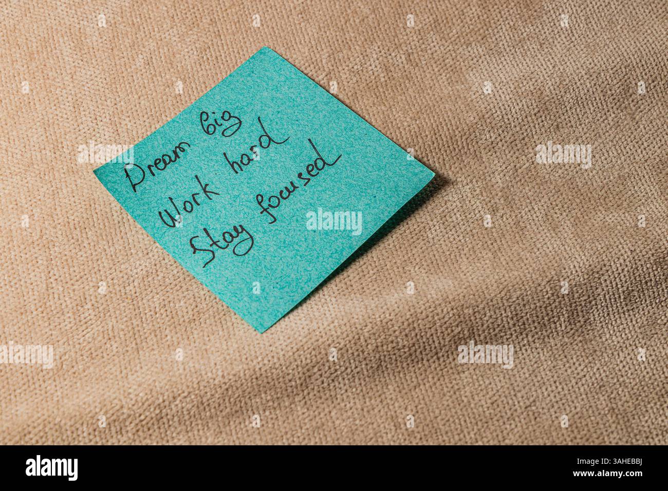 A colorful sticky note with an inspiring message lies on a soft surface ...