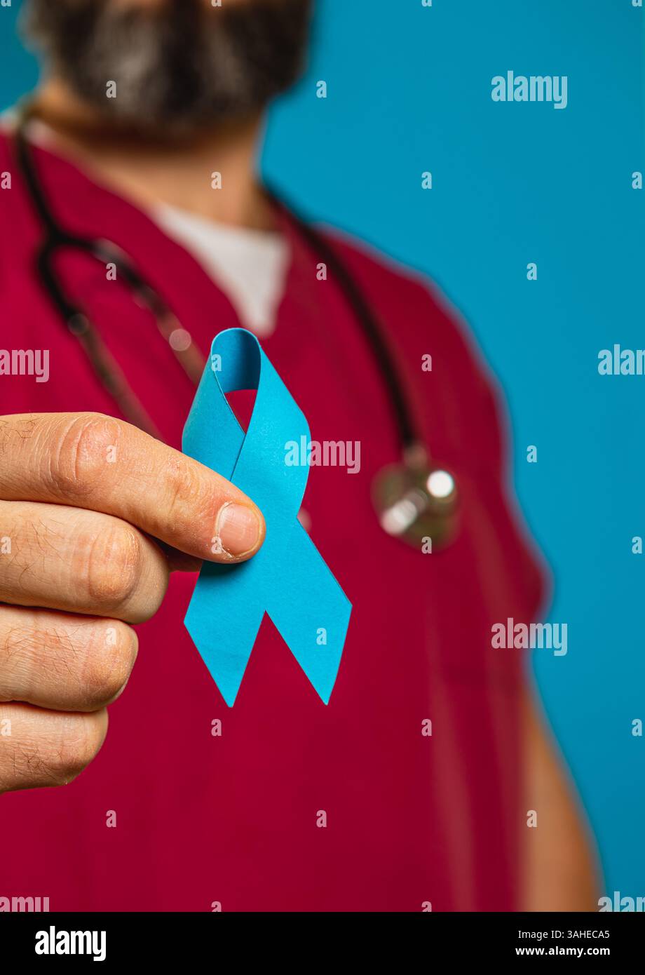 A healthcare professional in scrubs displays a blue ribbon symbolizing ...
