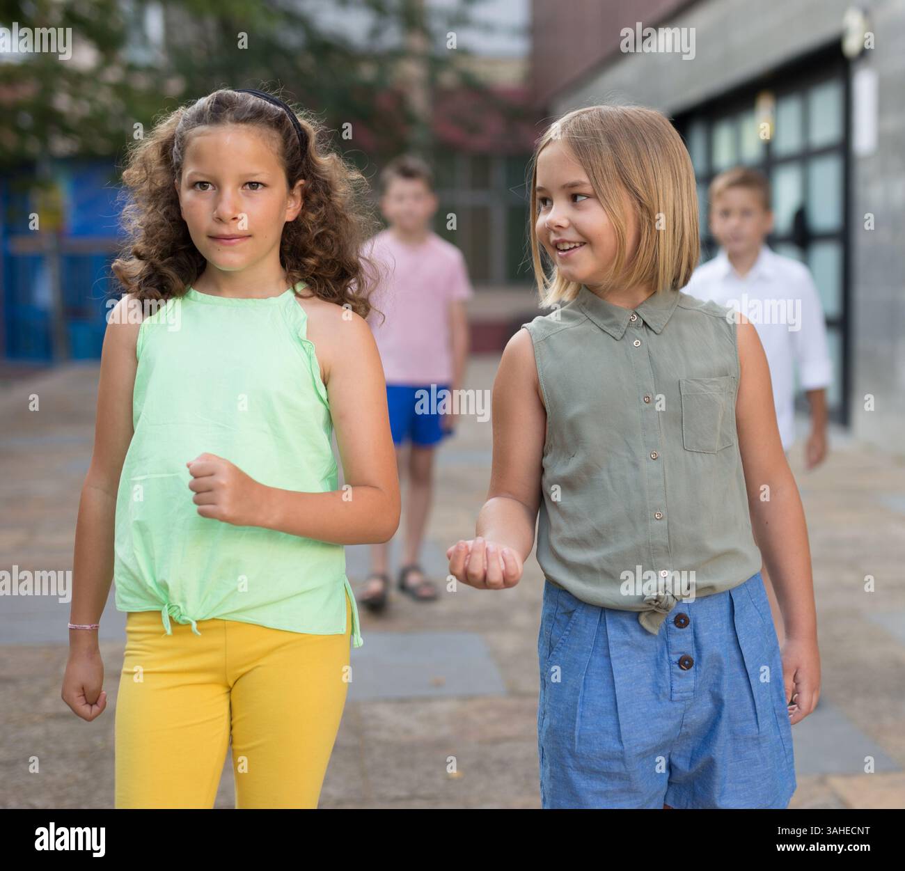 Friendly preteen girls talking during walk along city street Stock ...