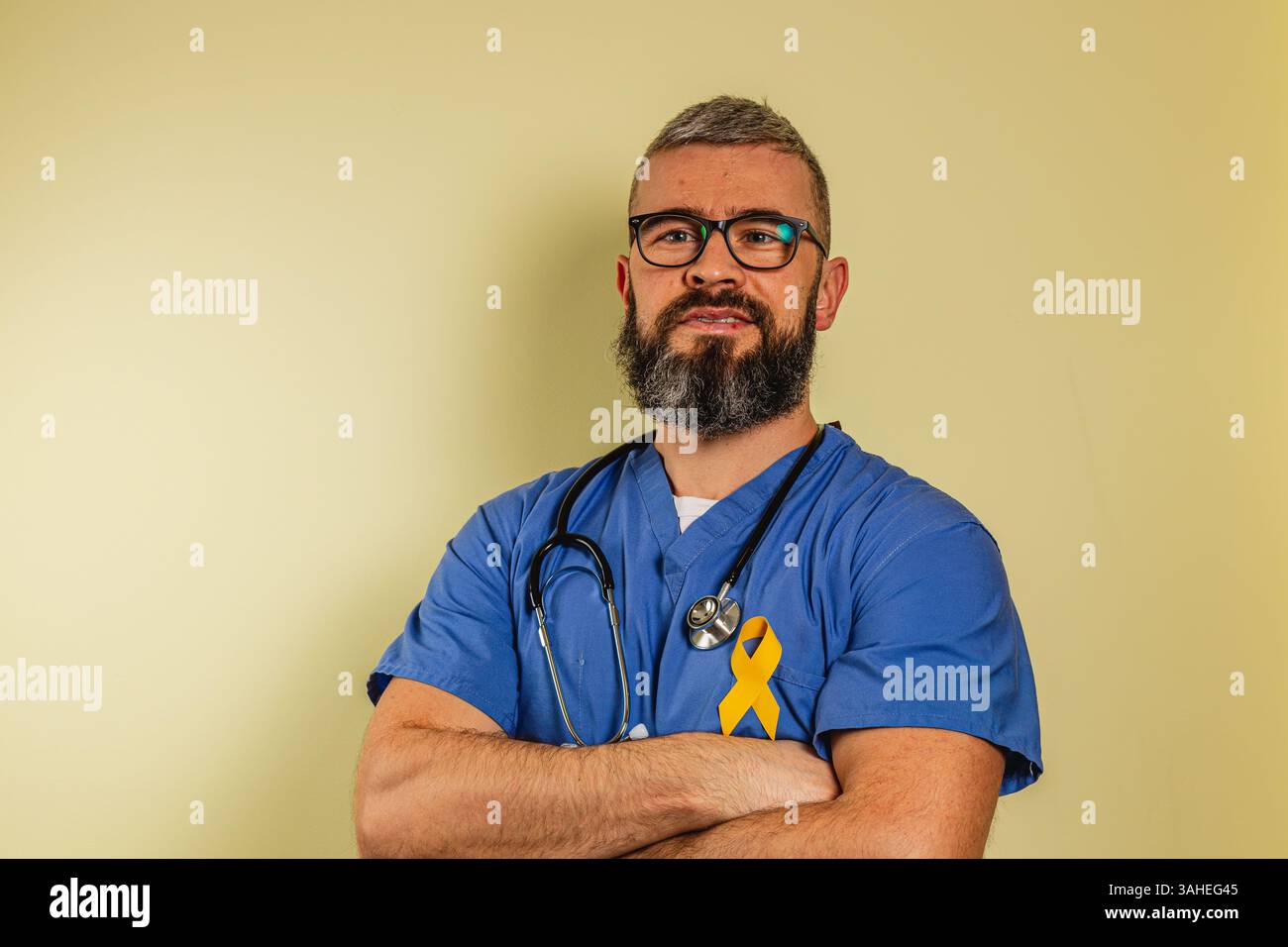 A confident male nurse in blue scrubs and glasses stands with arms ...