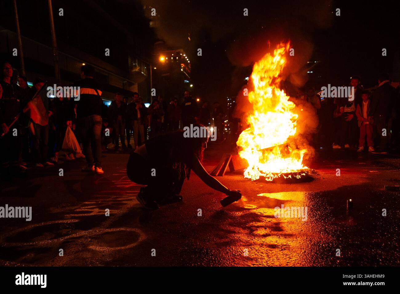 Demonstrators block a road with a bonfire and graffiti during a protest ...