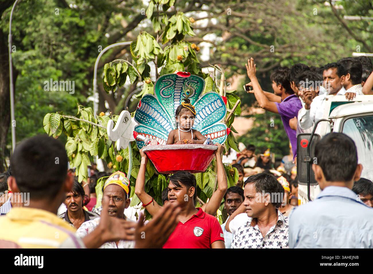 A child dressed as baby Krishna is carried in a decorative cradle ...