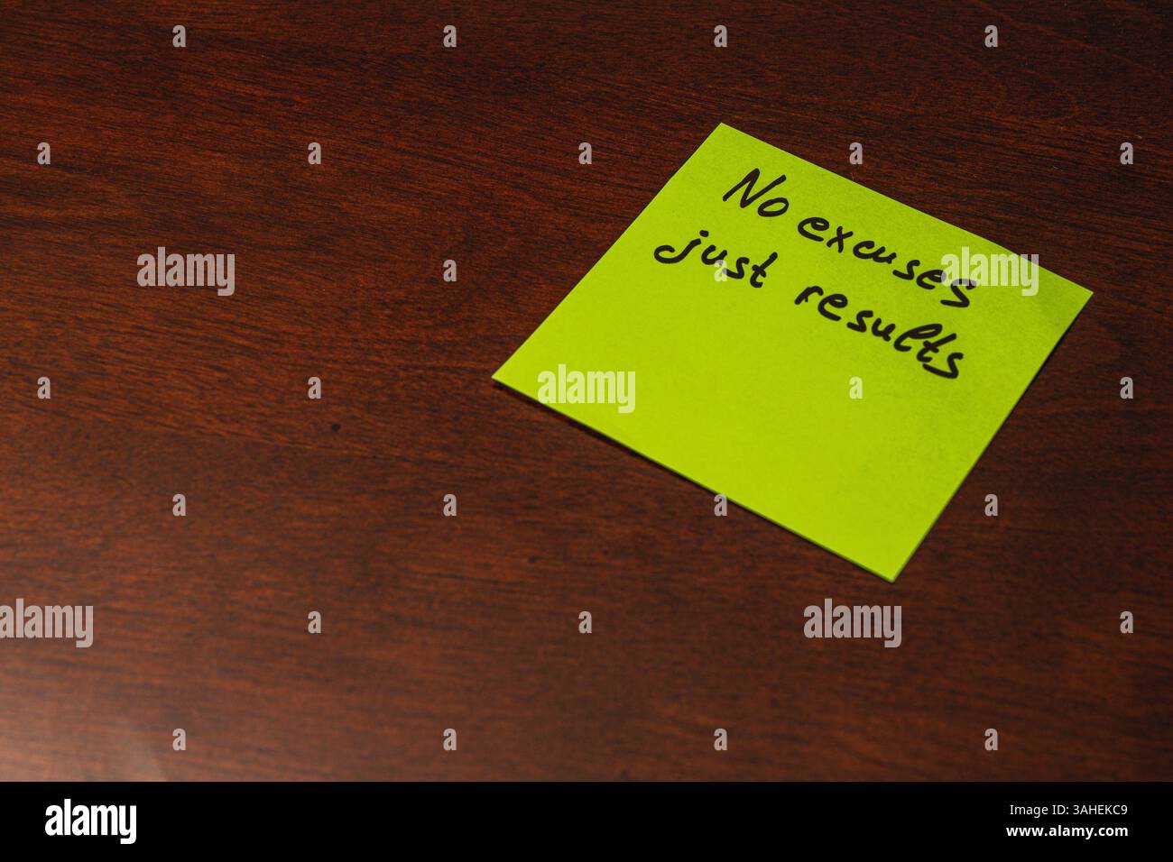 A bright yellow sticky note with handwritten motivational text sits on ...