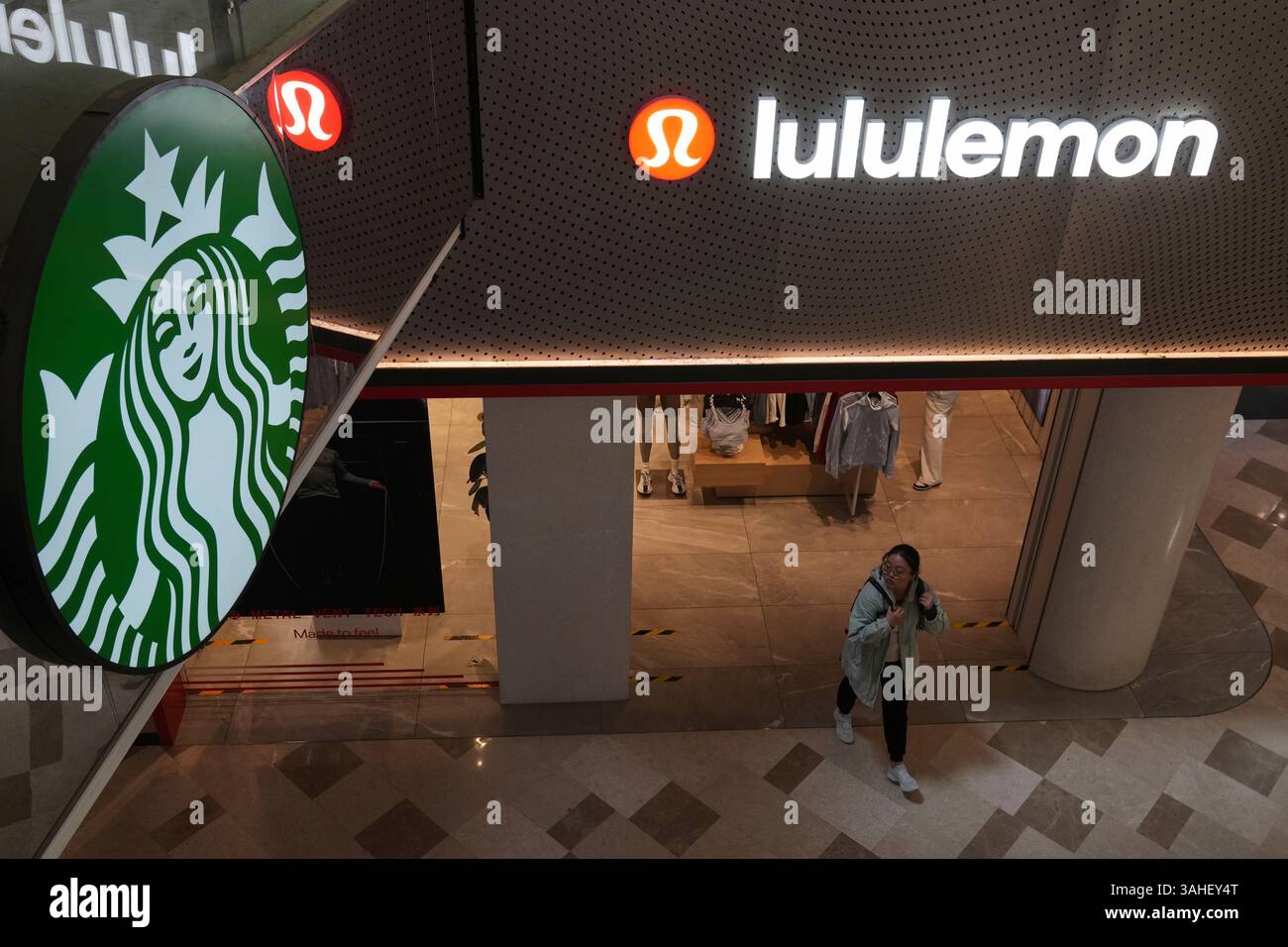 A woman walks out from a Lululemon store next to Starbucks cafe inside ...