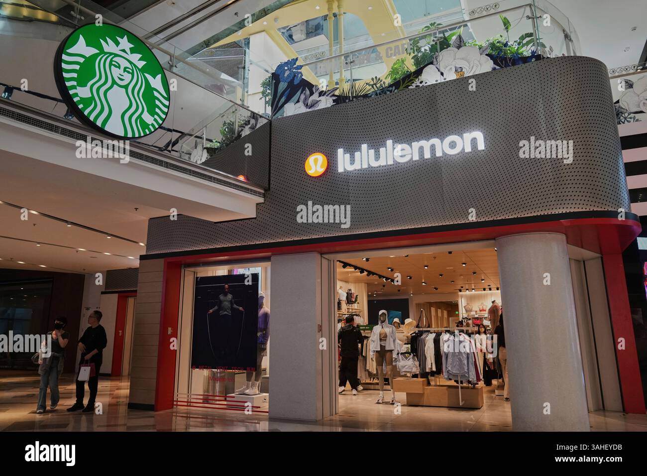 Shoppers tour by a Starbuck cafe and a Lululemon store inside a ...