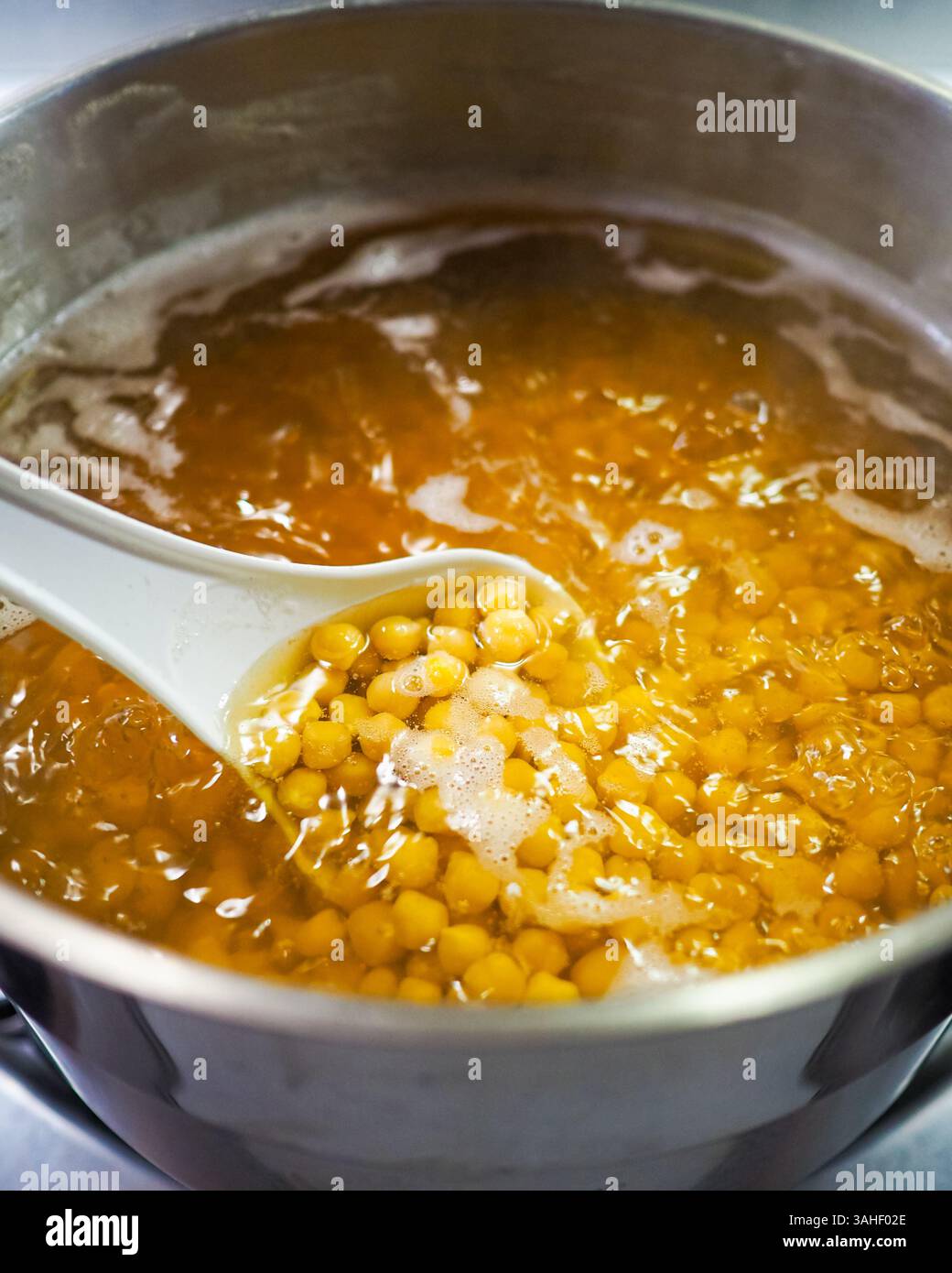 Chickpeas being cooked in boiling water in a saucepan. View from above ...