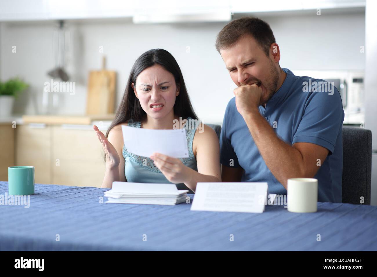 Angry interracial couple checking bank statement in the kitchen at home ...