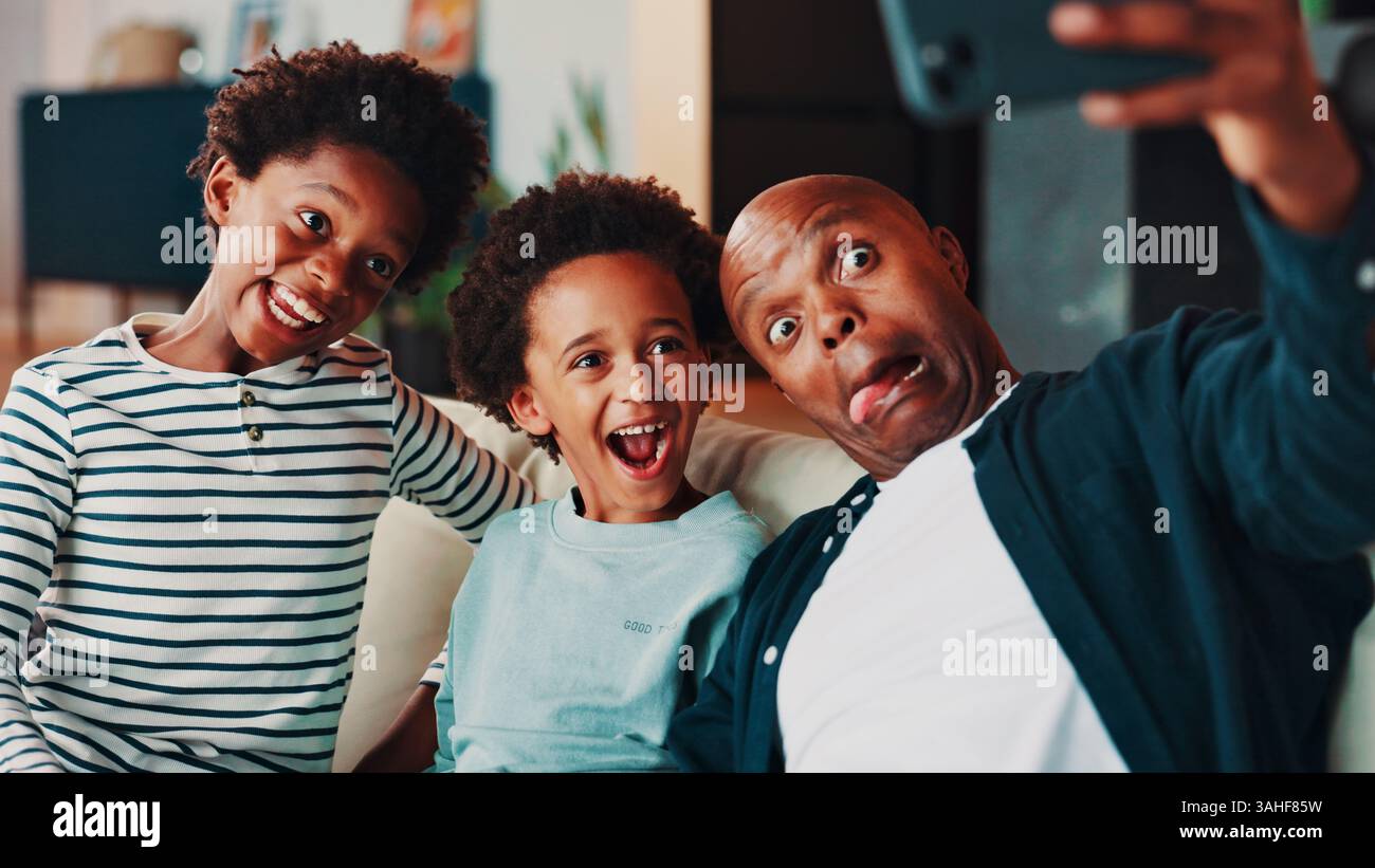 Selfie, funny face and dad with children on sofa for social media ...