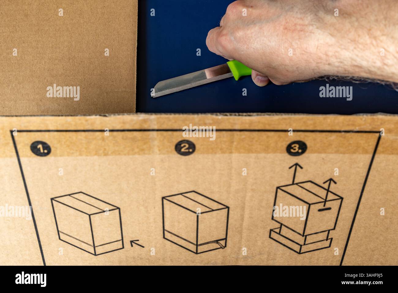 Unpacking a large gray cardboard box, knife on a cardboard box, opening ...