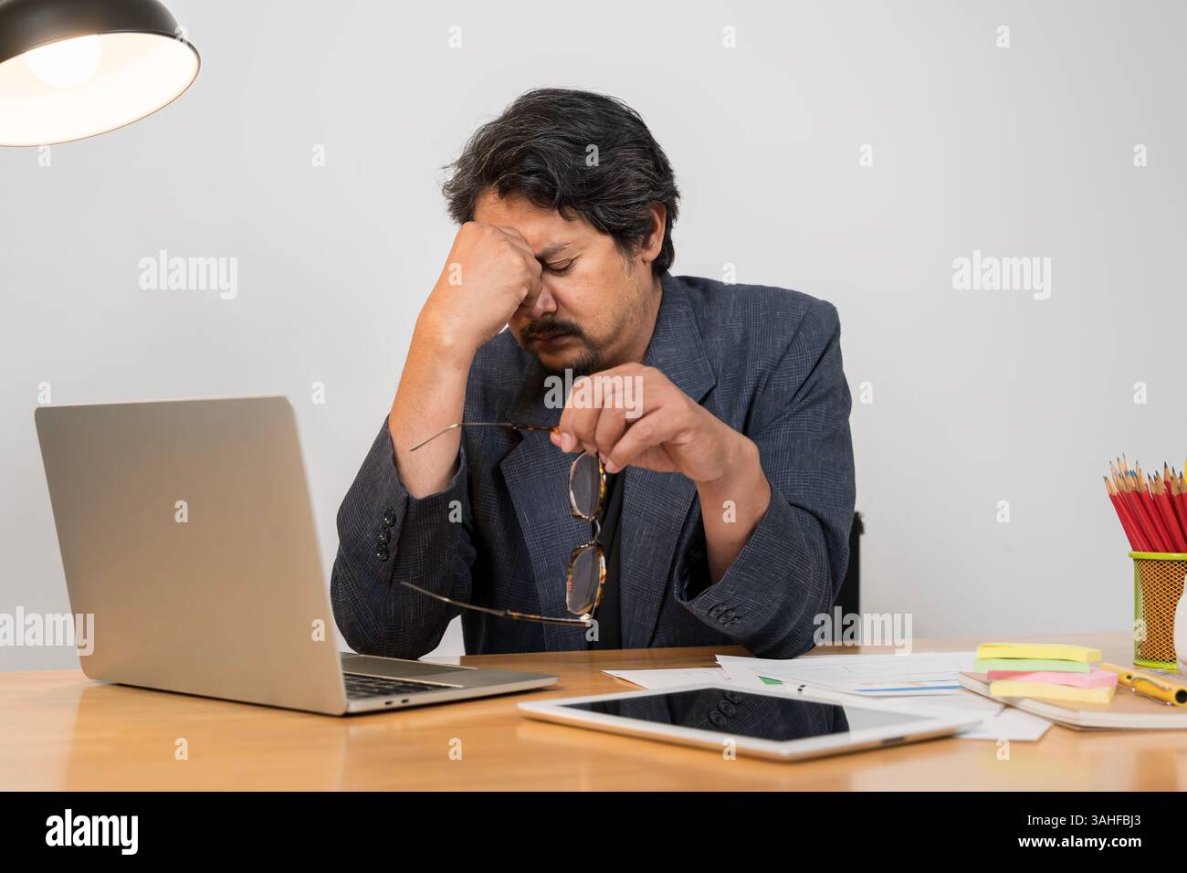 Fatigued indian man using laptop for working, a guy in casual wear is ...