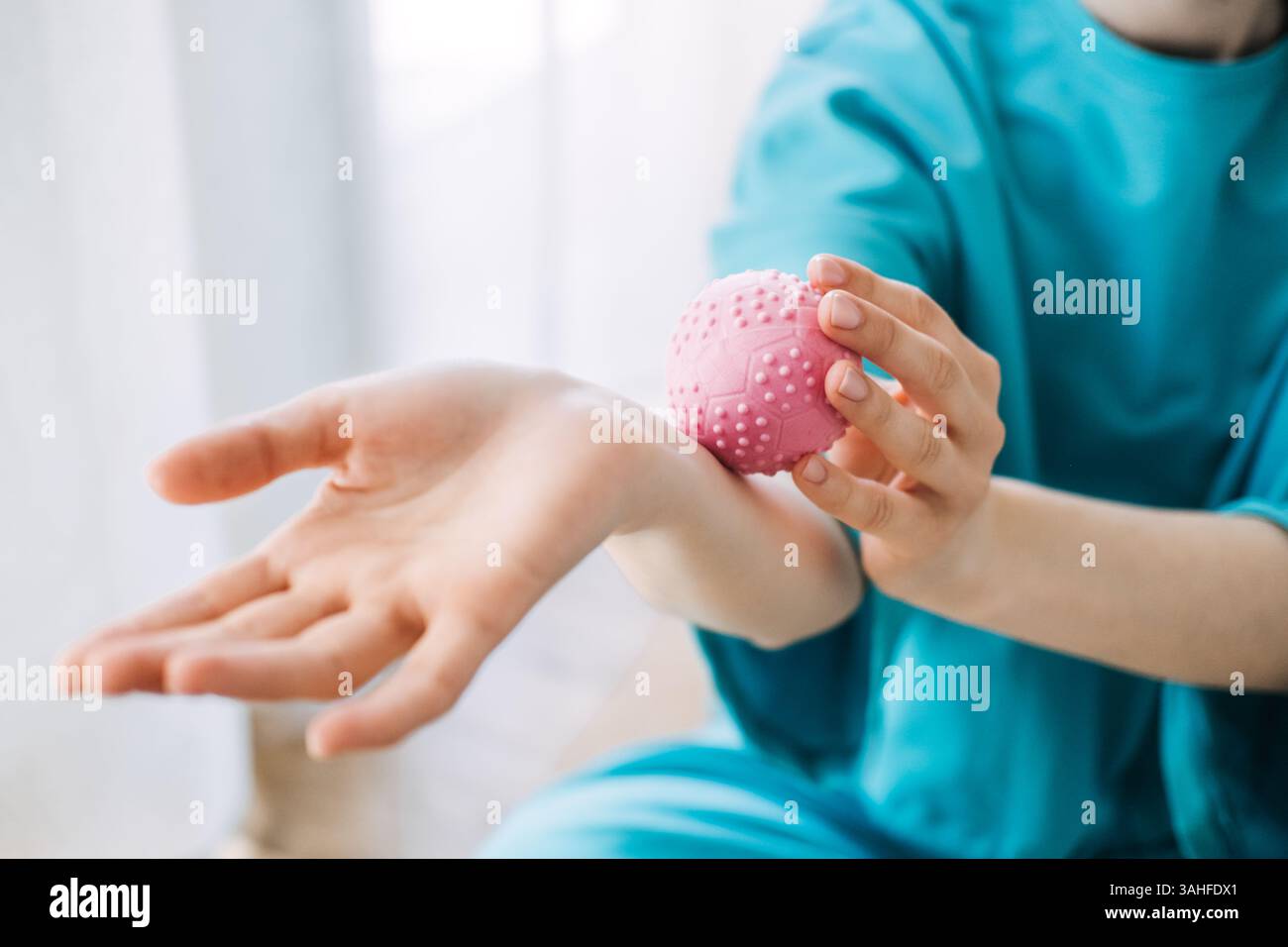 Close-up of woman applying a pink massage ball to her forearm. Tactile ...