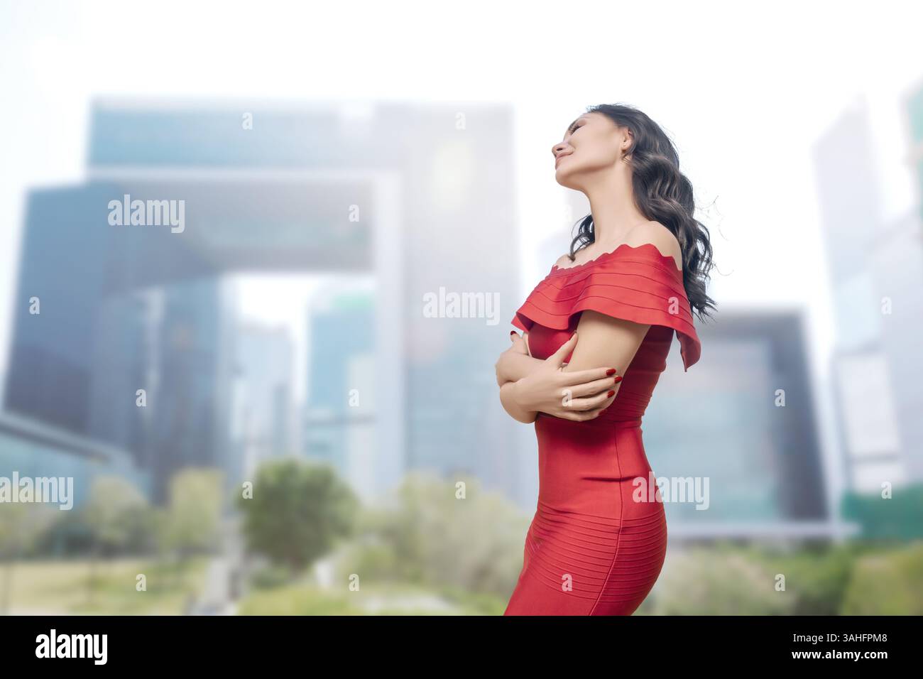 An elegant Asian woman in a stunning red dress striking a pose in front ...