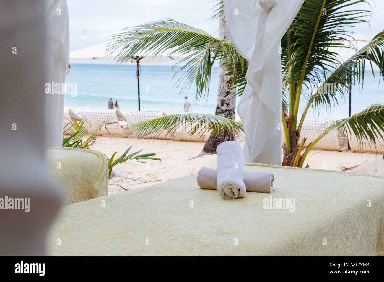 A tranquil beachfront massage setup features two massage tables under a ...