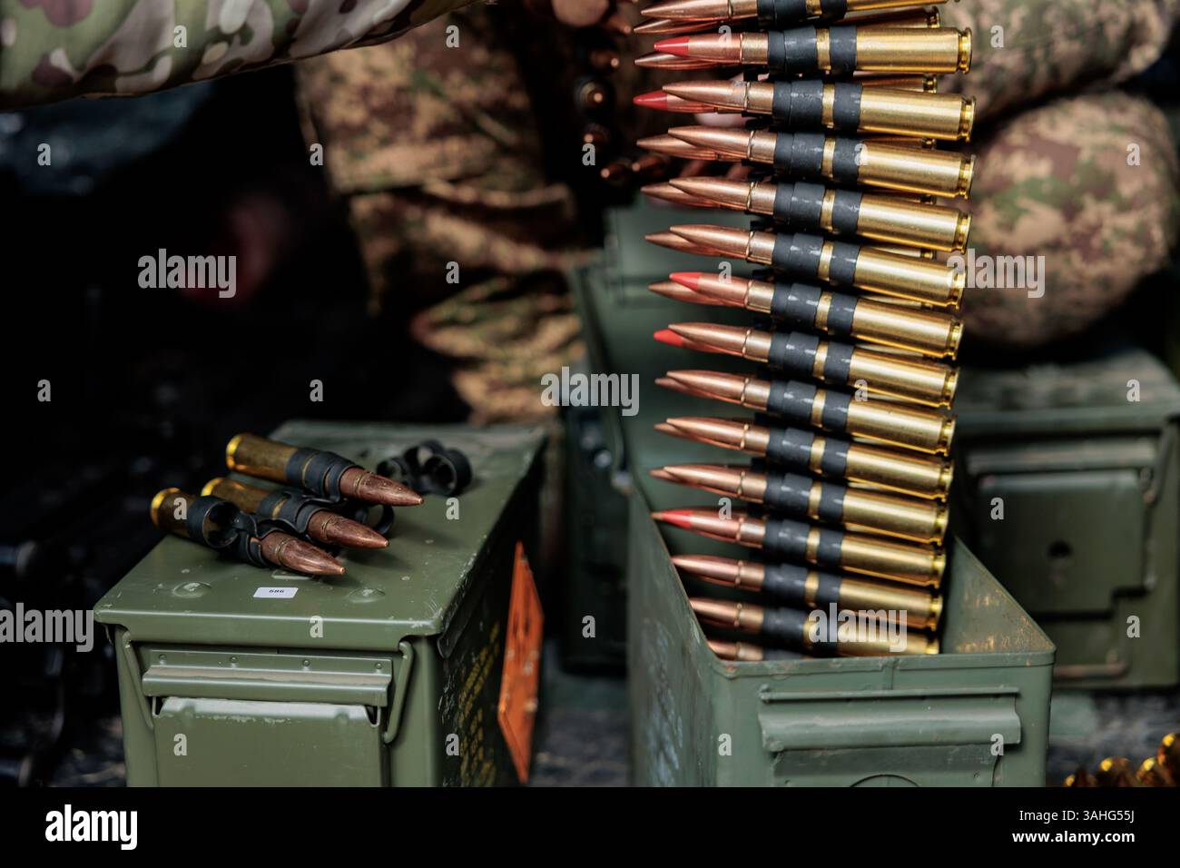 A soldier takes machine gun cartridges out of a metallic ammunition box ...