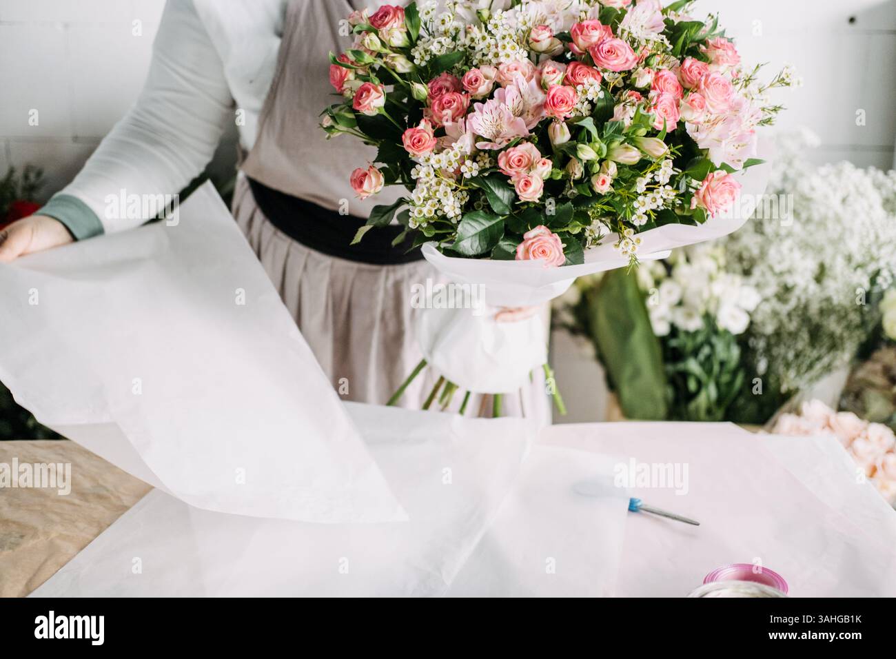 Florist presenting a completed bouquet of mixed pink flowers wrapped in ...