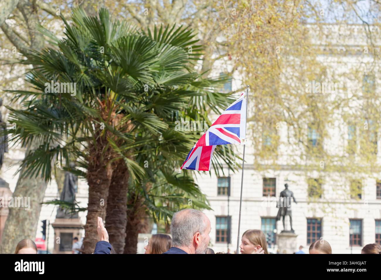 A tour guide in Parliament Square, gesturing to follow him as he talks ...