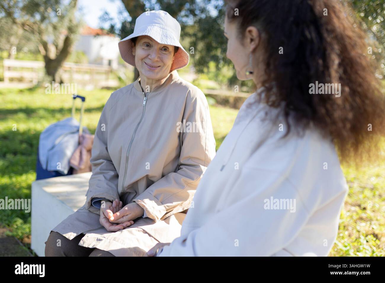 Doctor visiting elderly woman sitting on bench in park Stock Photo - Alamy