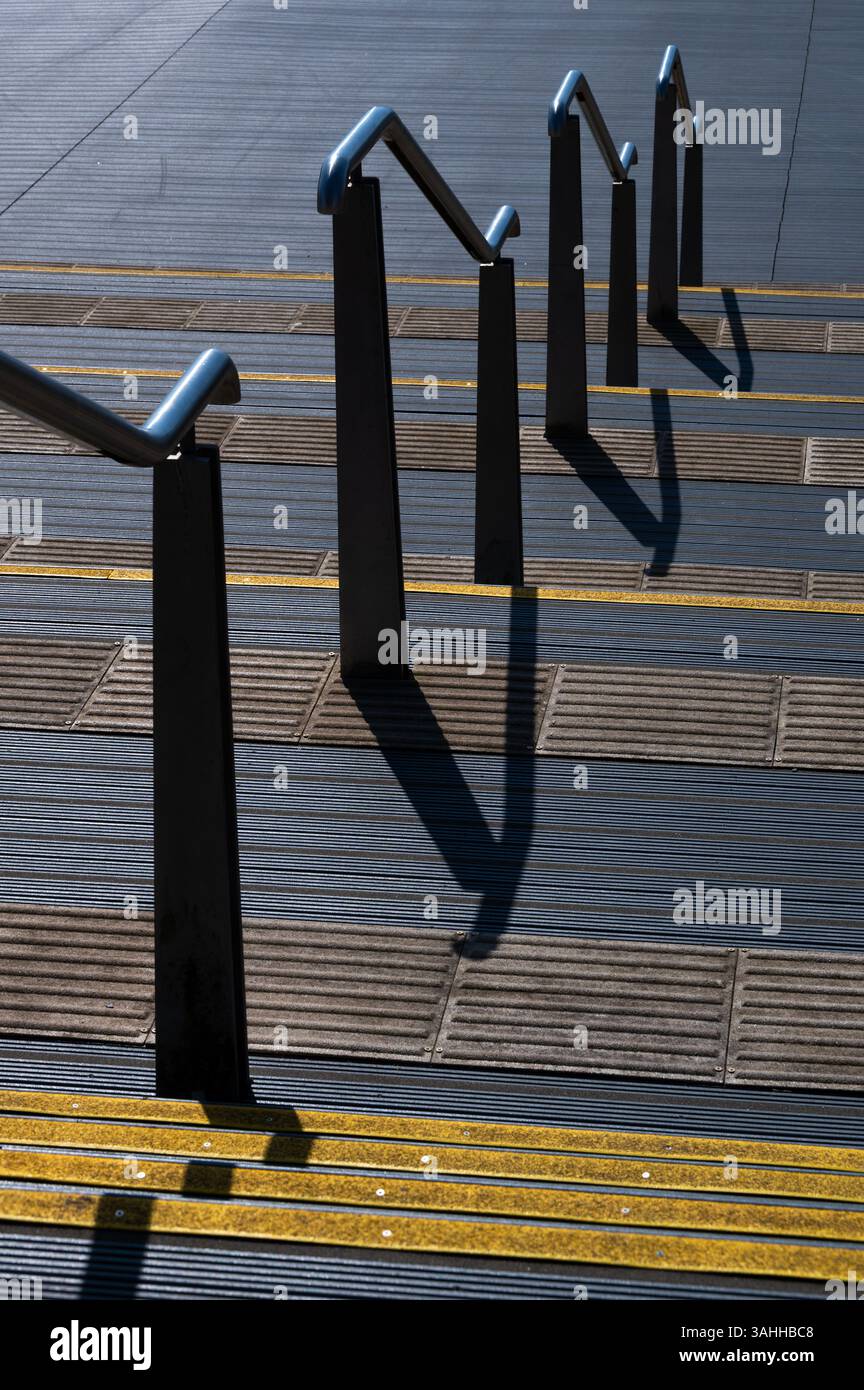 Railings cast shadows on steps in Cardiff Bay on a sunny spring ...