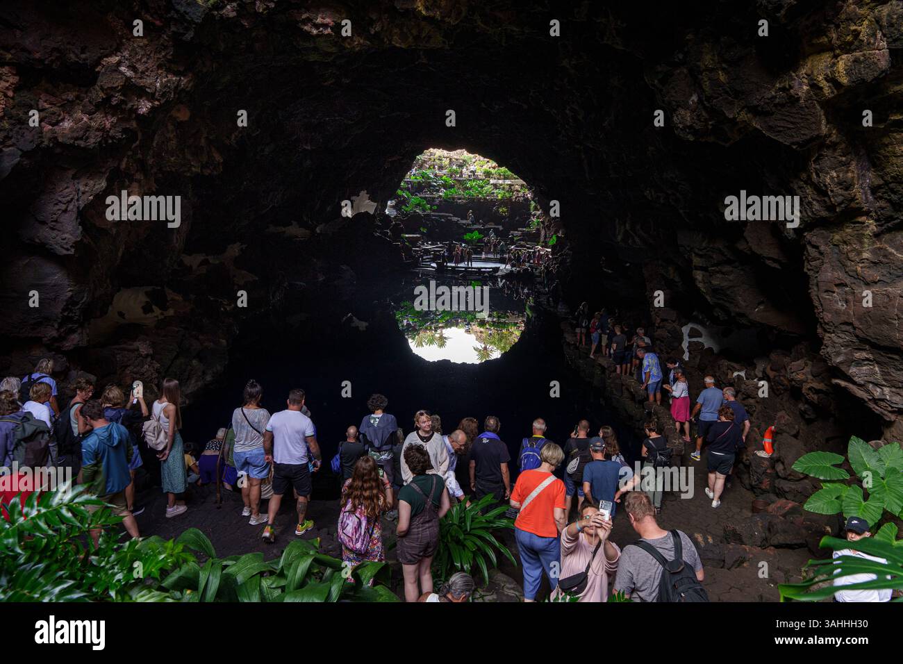 Tourists visiting the underground volcanic cave and reflective natural ...