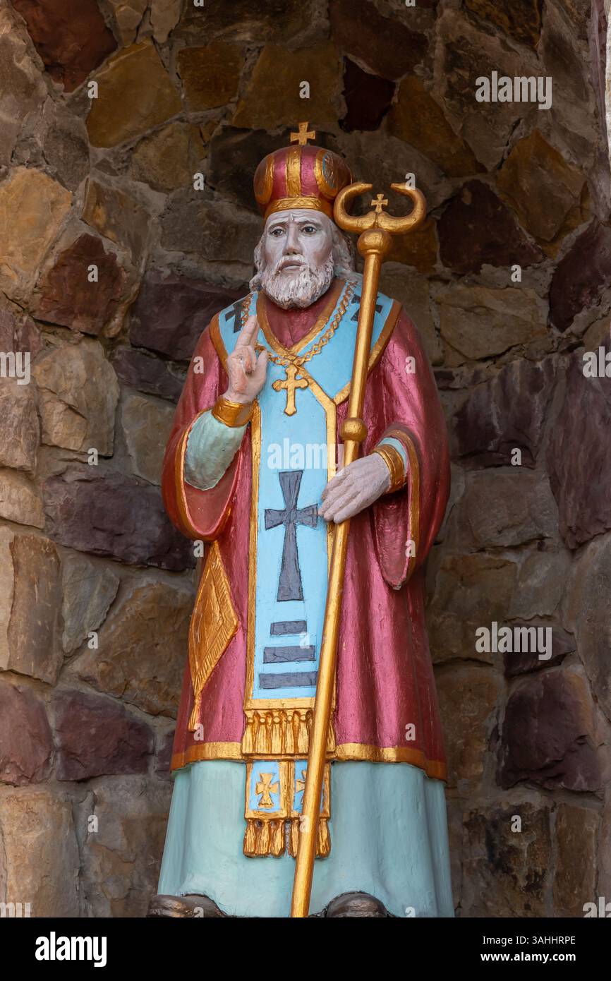 The statue depicts a bearded saint in vibrant robes, holding a staff ...
