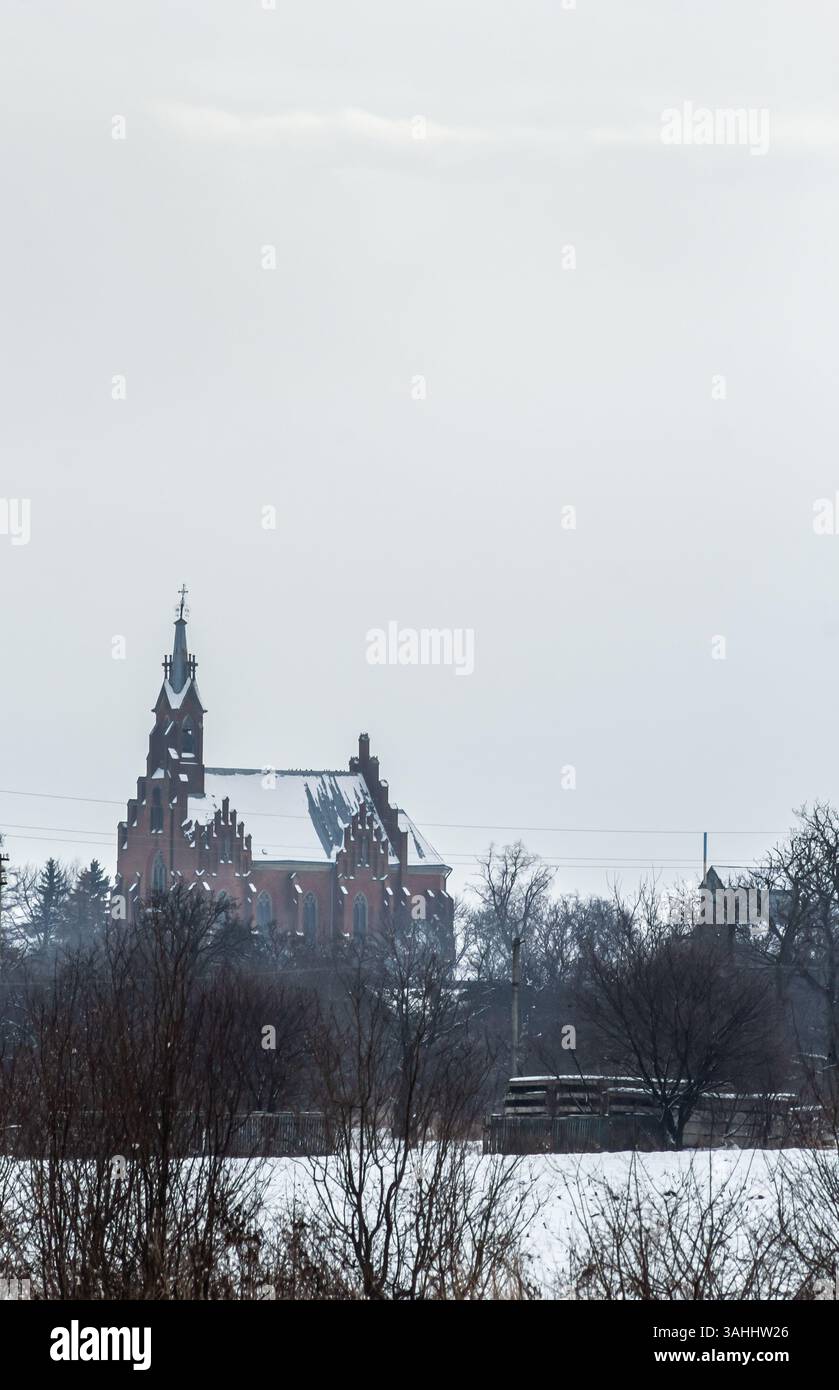 A large church stands quietly in a winter landscape, surrounded by ...