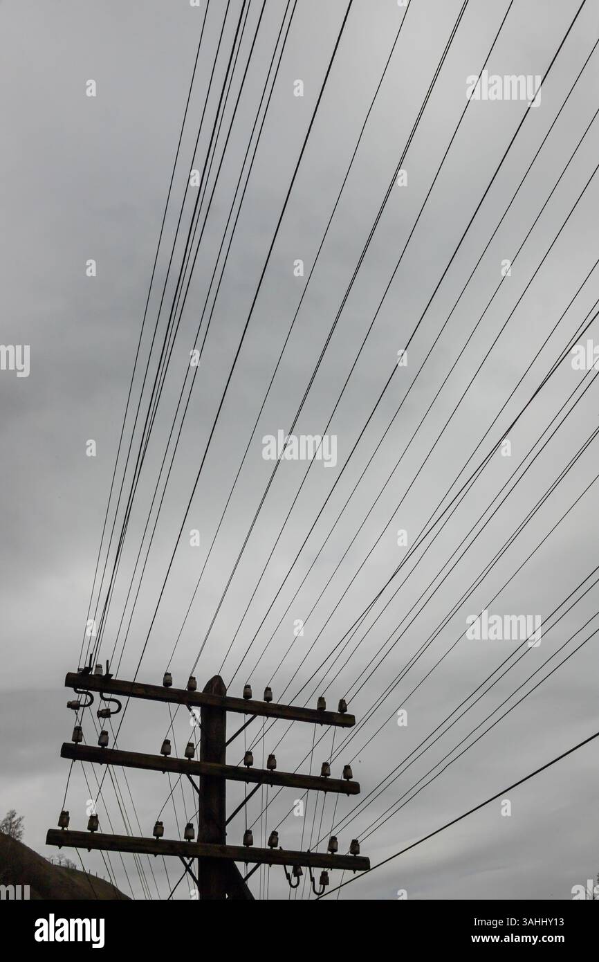 Dark clouds cover the sky as multiple power lines extend horizontally ...