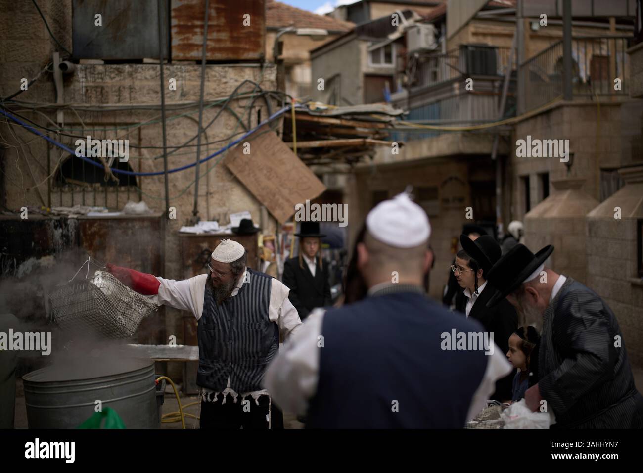 An ultra-Orthodox Jewish man dips cooking utensils in boiling water to ...