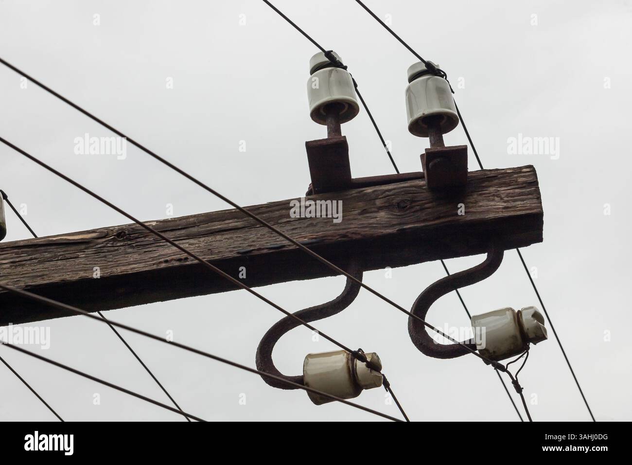 A wooden utility pole supports power lines, featuring distinct ceramic ...