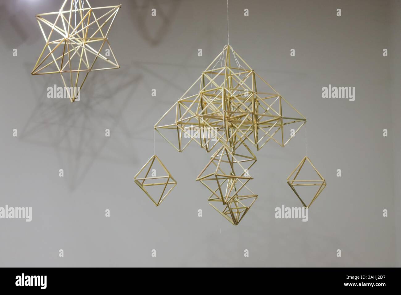 An intricate geometric mobile crafted from wooden sticks hangs ...