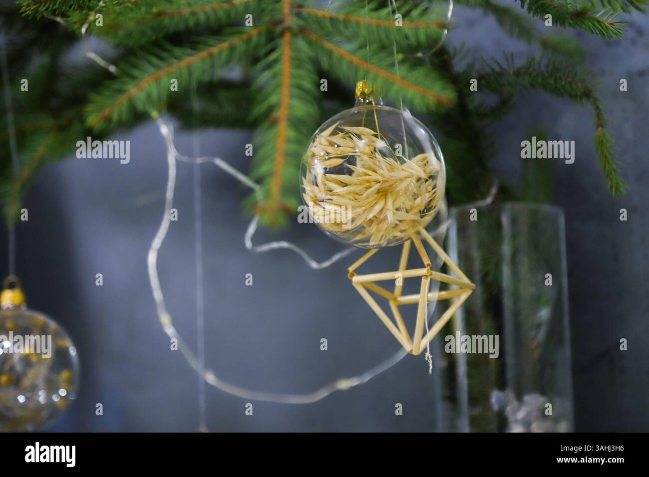 A creative holiday ornament showcases strands of straw enclosed in a ...