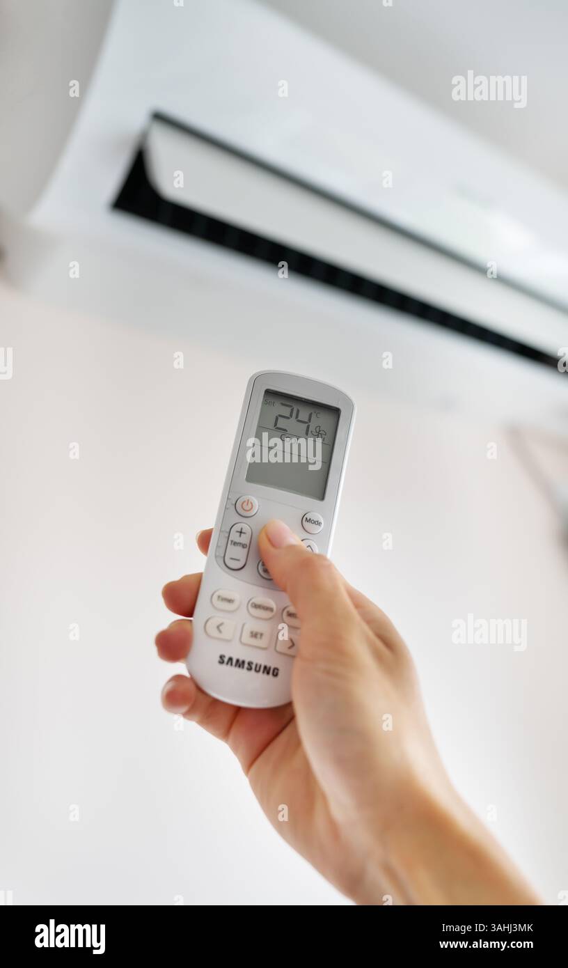 Hand holding remote control adjusting Samsung air conditioner ...