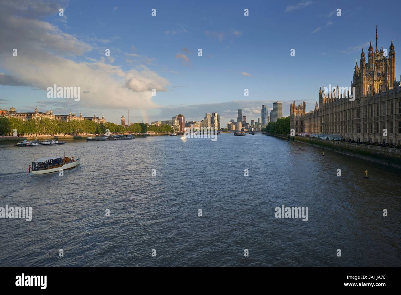 River Thames with boat and London skyline under cloudy blue sky near ...