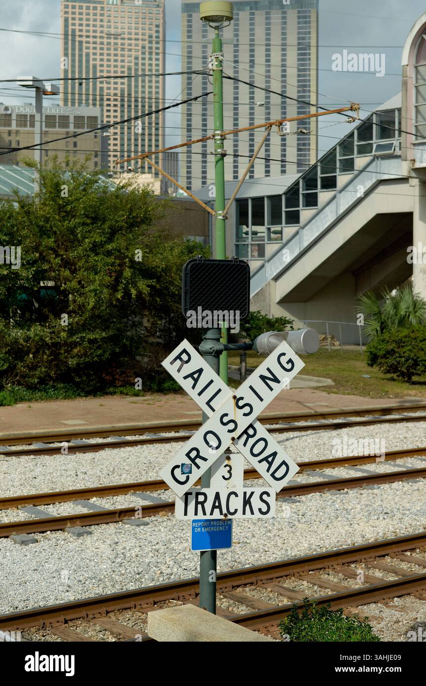 Railway crossing sign near train tracks and urban buildings in a city ...