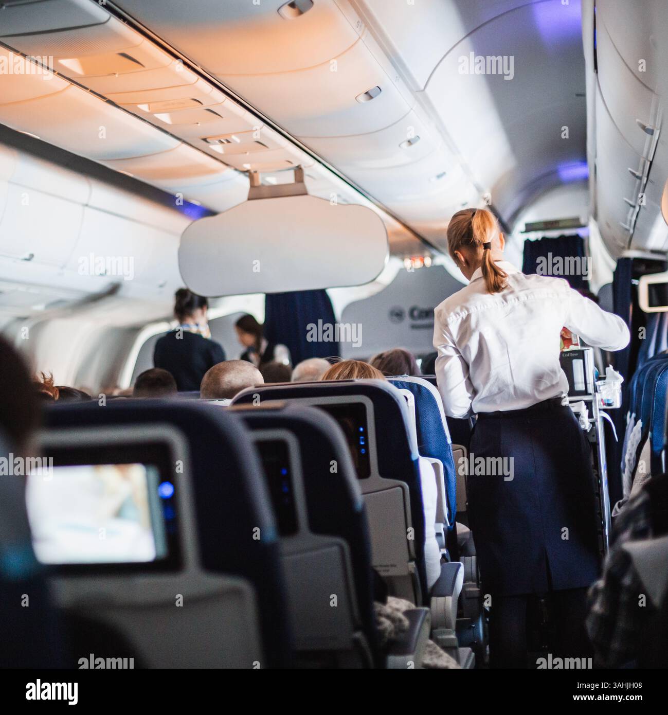 Interior of airplane with passengers on seats and stewardess in uniform ...