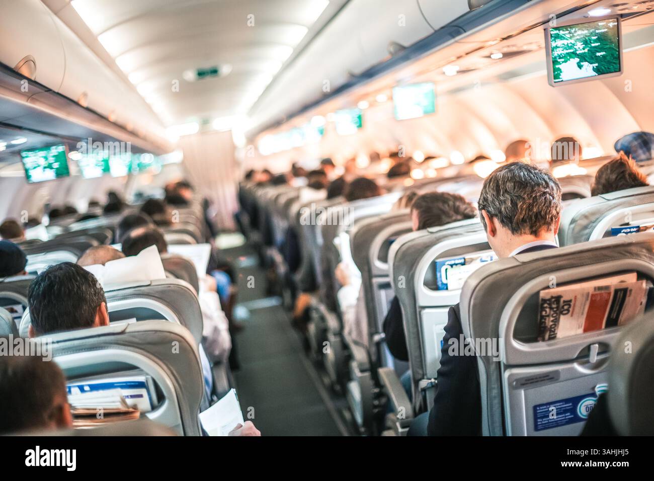 Interior of airplane with passengers on seats and stewardess in uniform ...