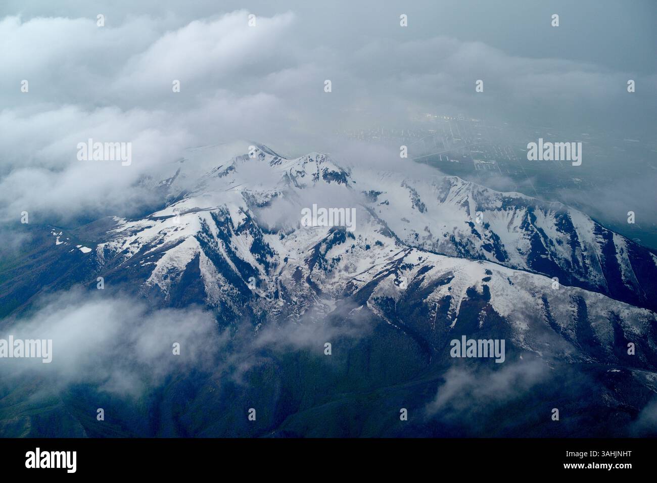 Aerial view of snowy mountain peaks surrounded by clouds and mist ...
