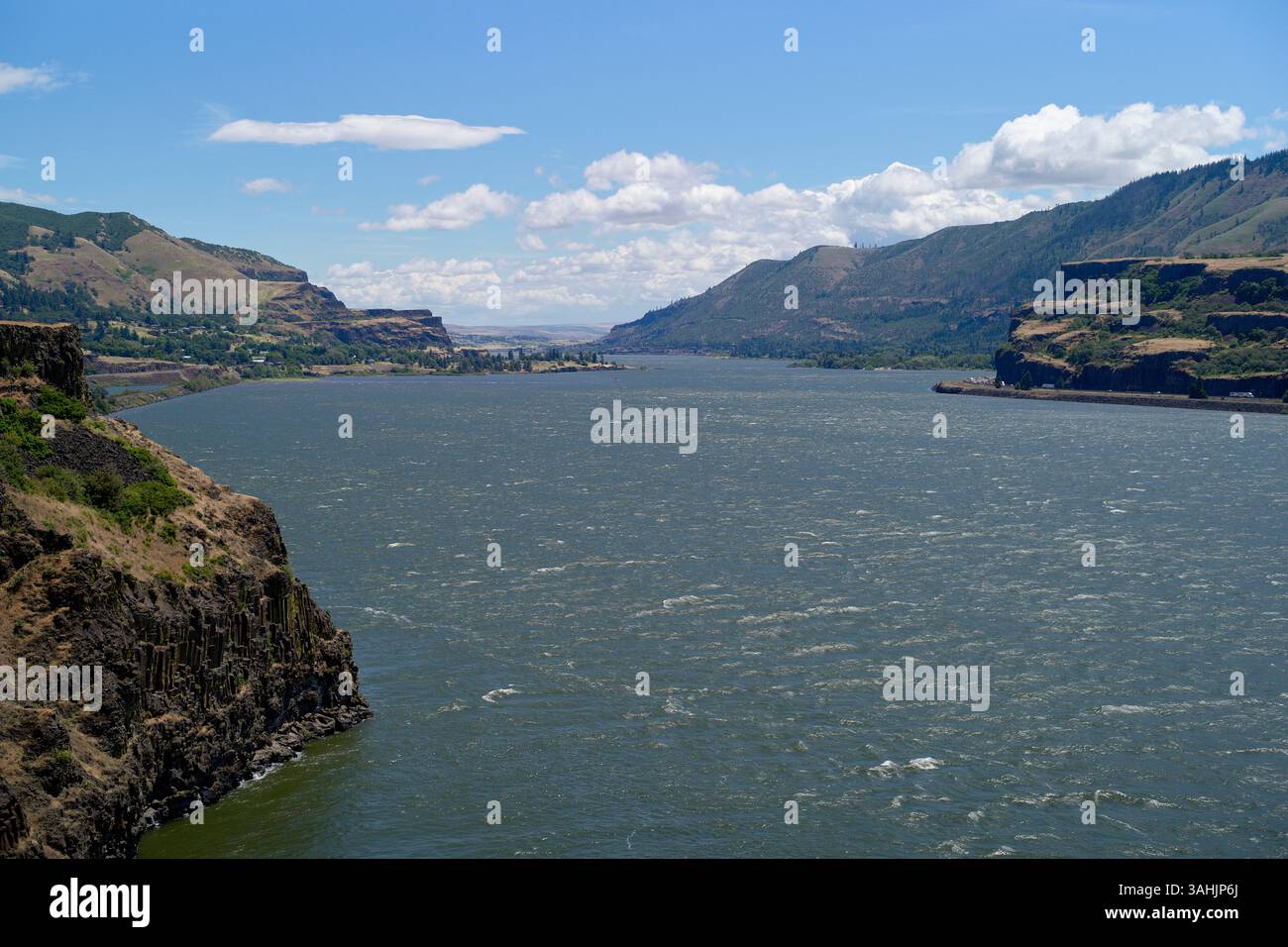 Scenic river with rugged cliffs and lush greenery under a bright blue ...