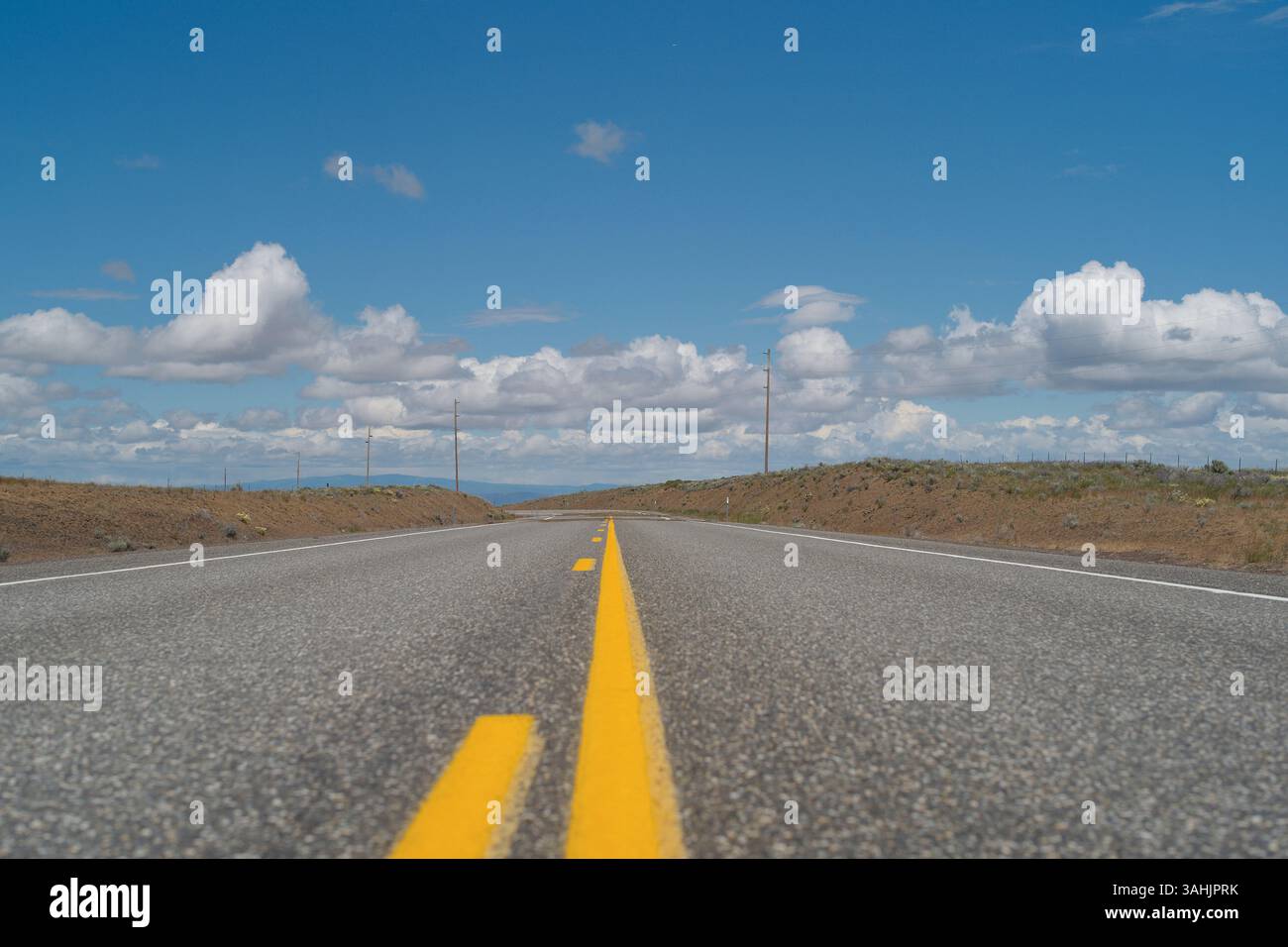 Open road leading into the horizon under a bright blue sky with ...