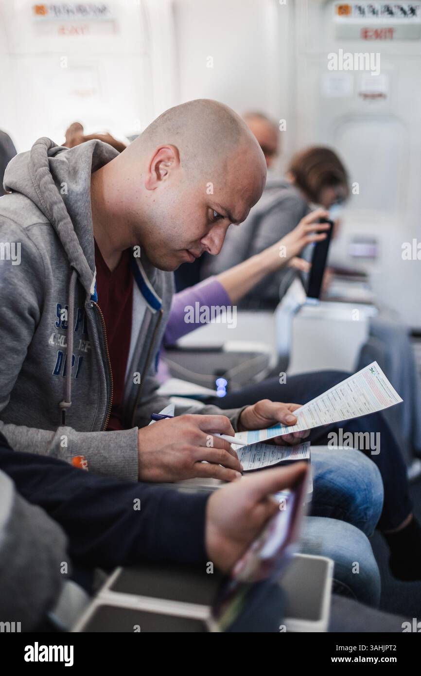 Male traveler filling immigration form on flight to visit destination ...