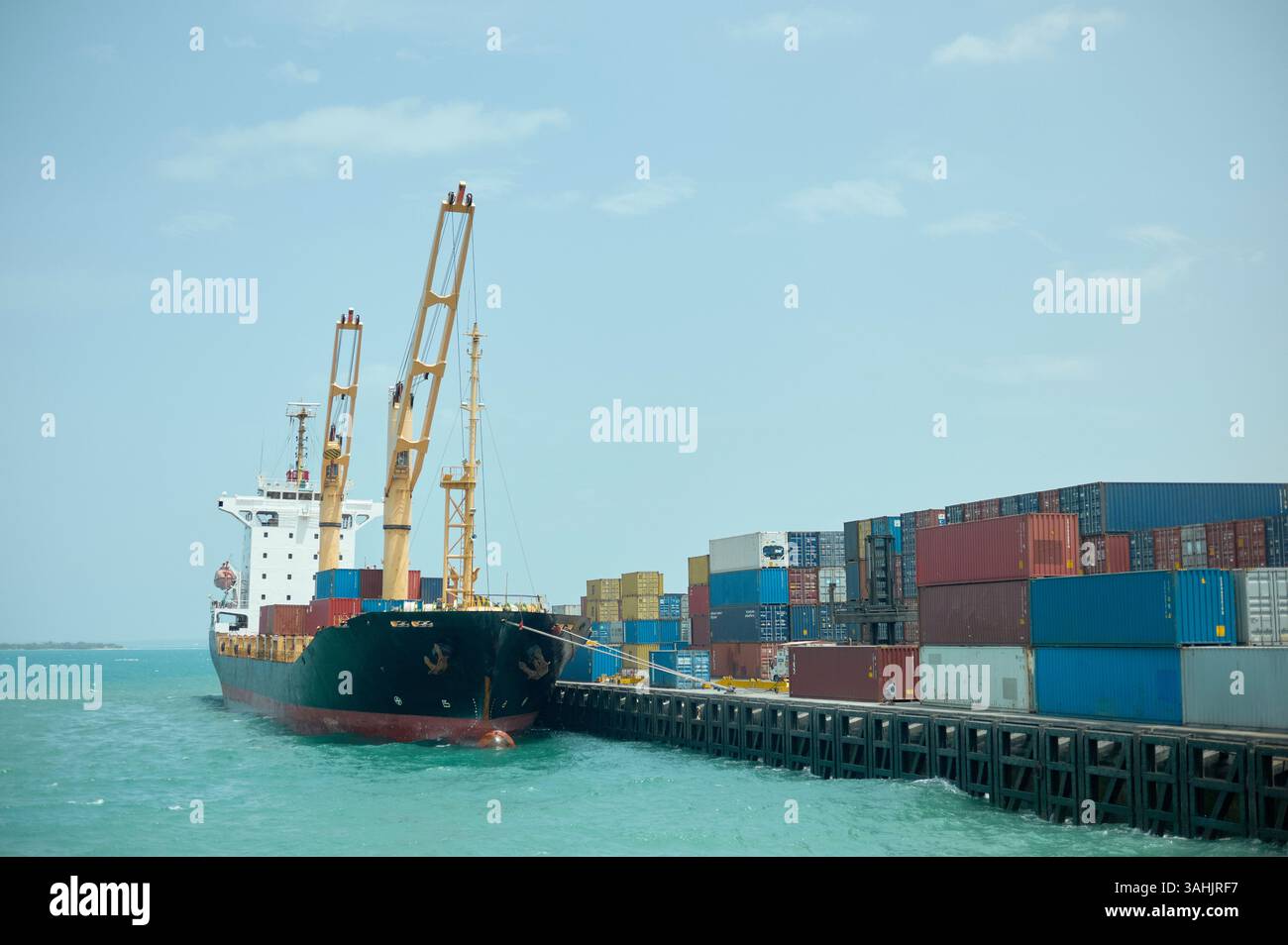 Cargo ship docked at a bustling port with stacked colorful shipping ...