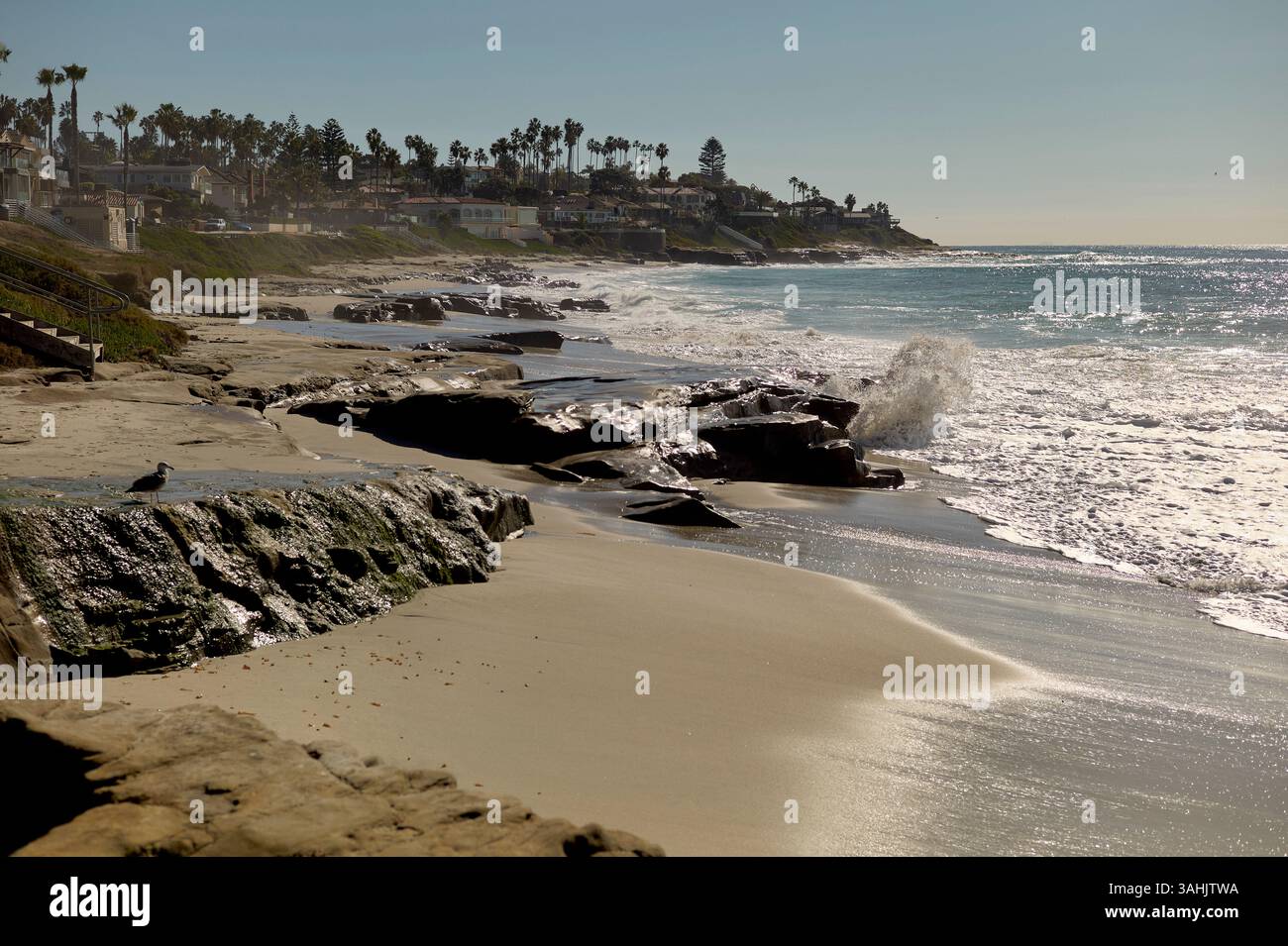 Coastal landscape with waves crashing on rocky shore under clear sky ...