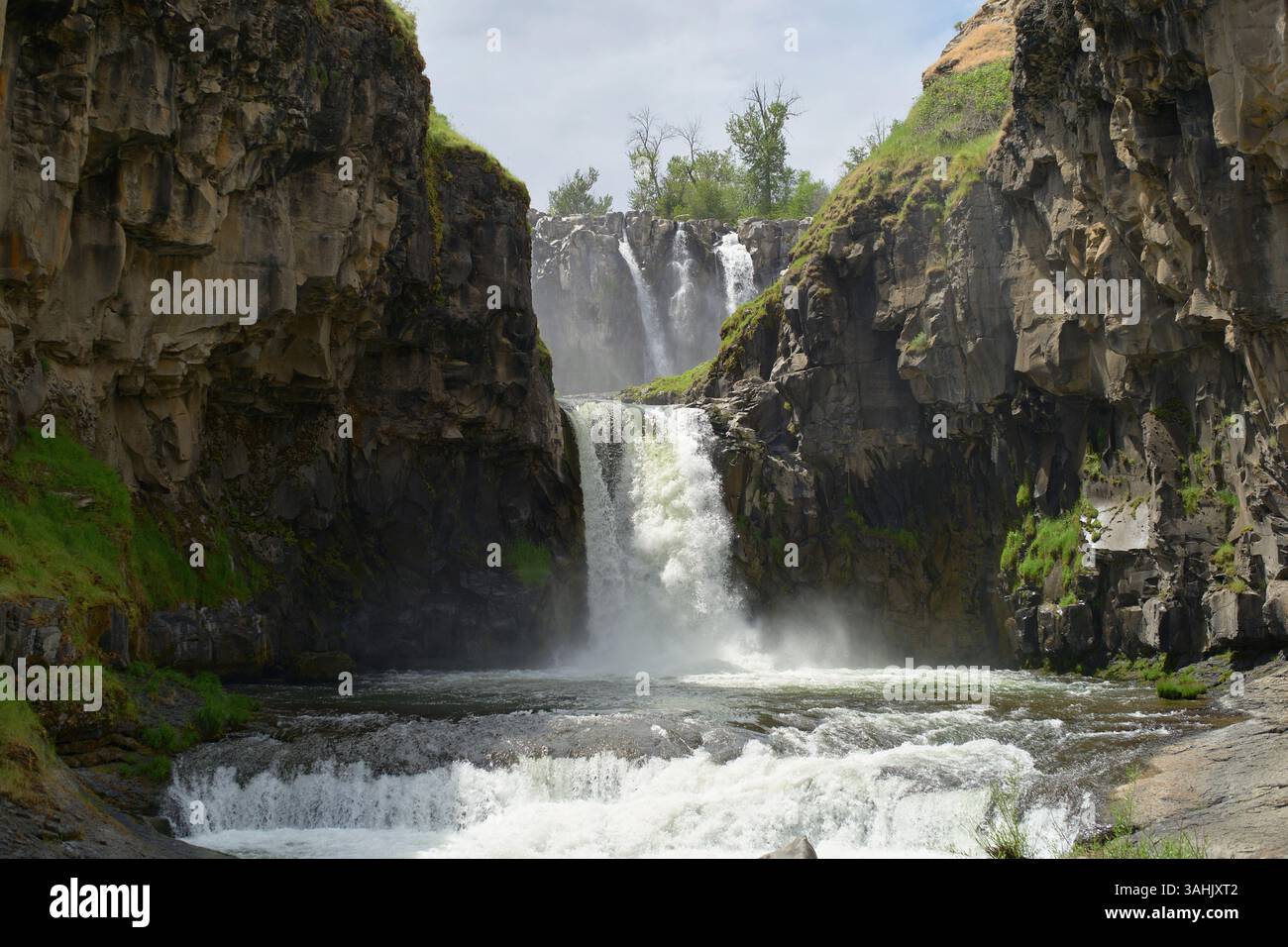 Majestic waterfall cascading between rocky cliffs with lush greenery ...