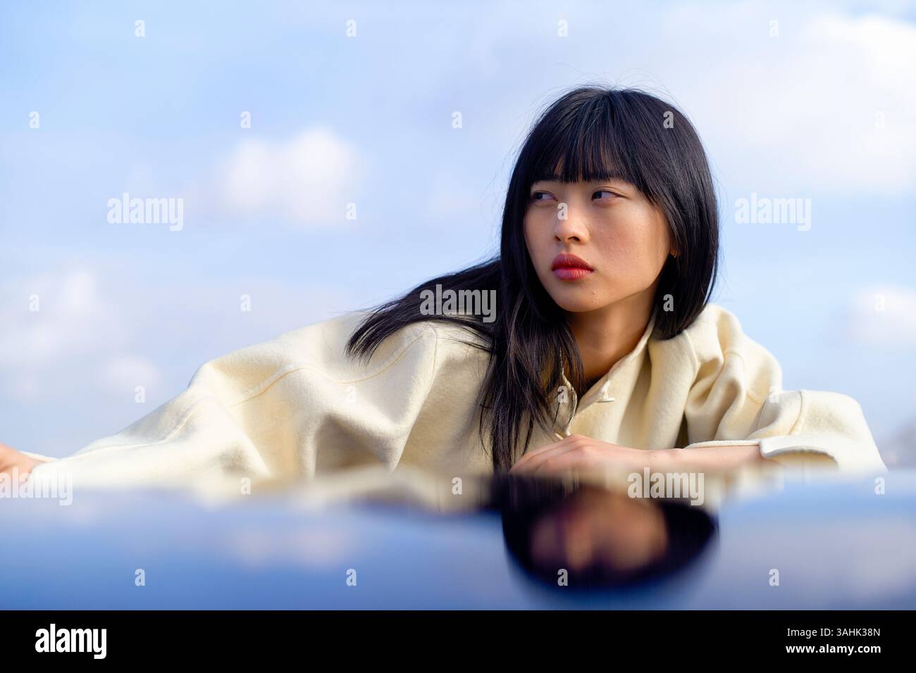 Woman in a white blouse lying down, gazing thoughtfully into the ...