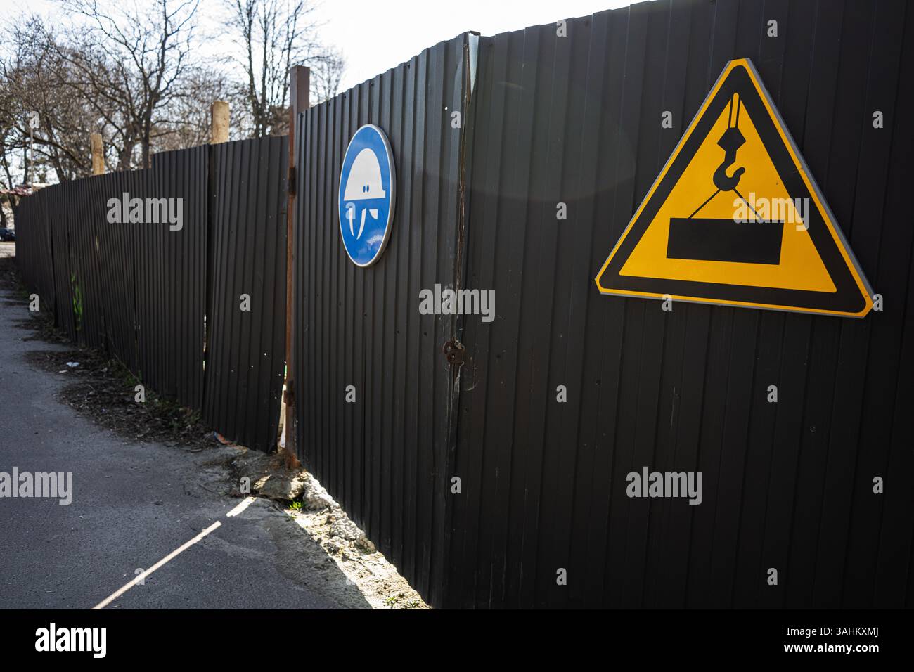 Warning signs on a construction site fence indicating safety ...