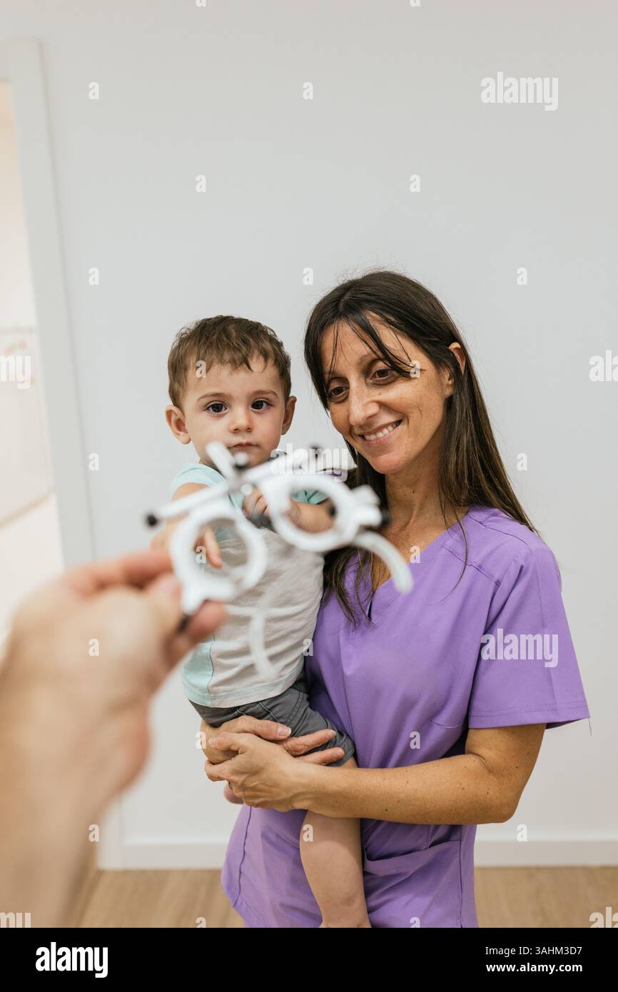 Pediatric optometrist holding a baby during a vision test Stock Photo ...