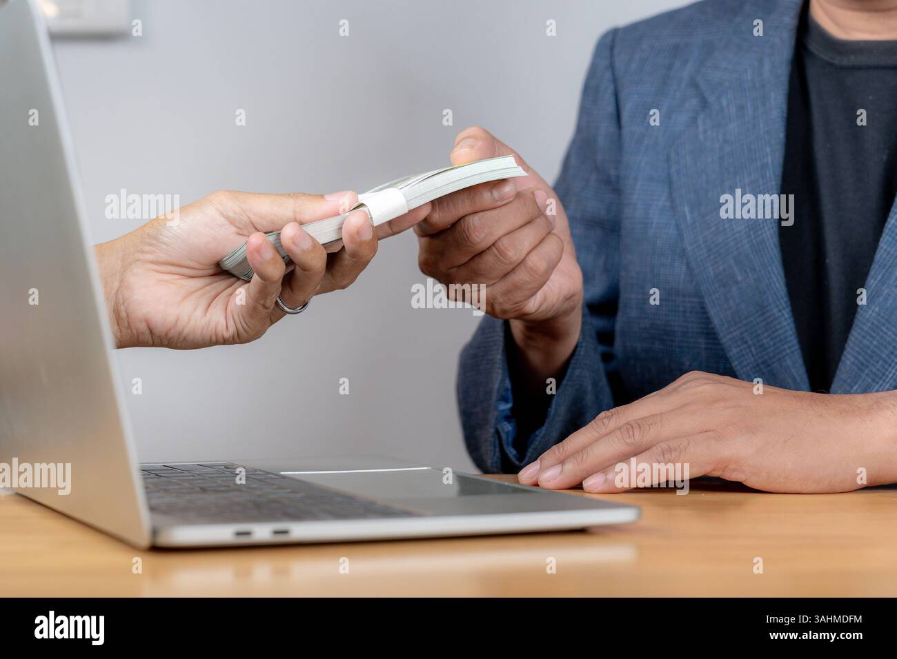 A hand extends from a laptop screen, delivering money to a businessman ...