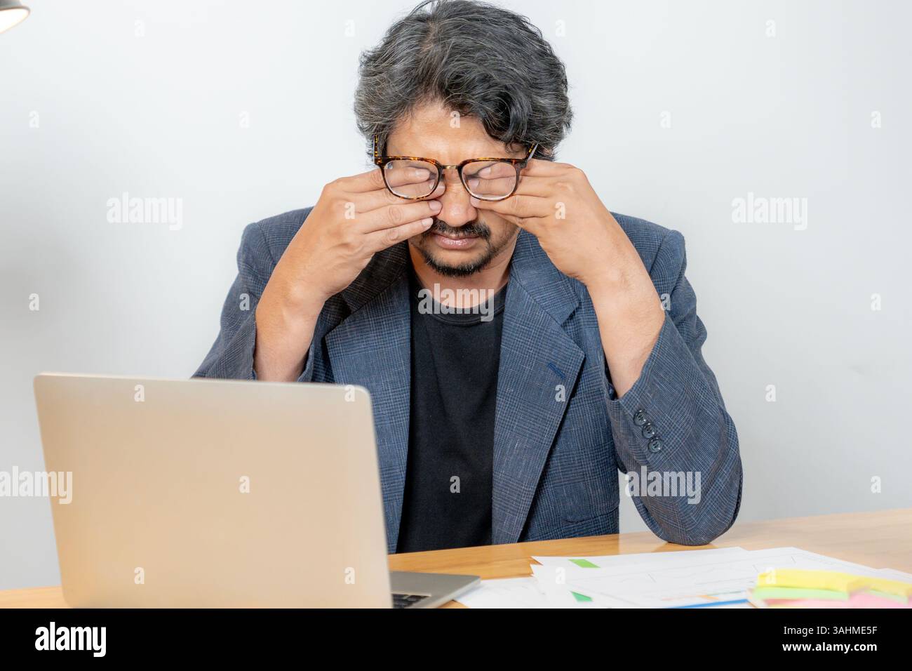 A young businessman staring at his computer screen for hours, rubbing ...
