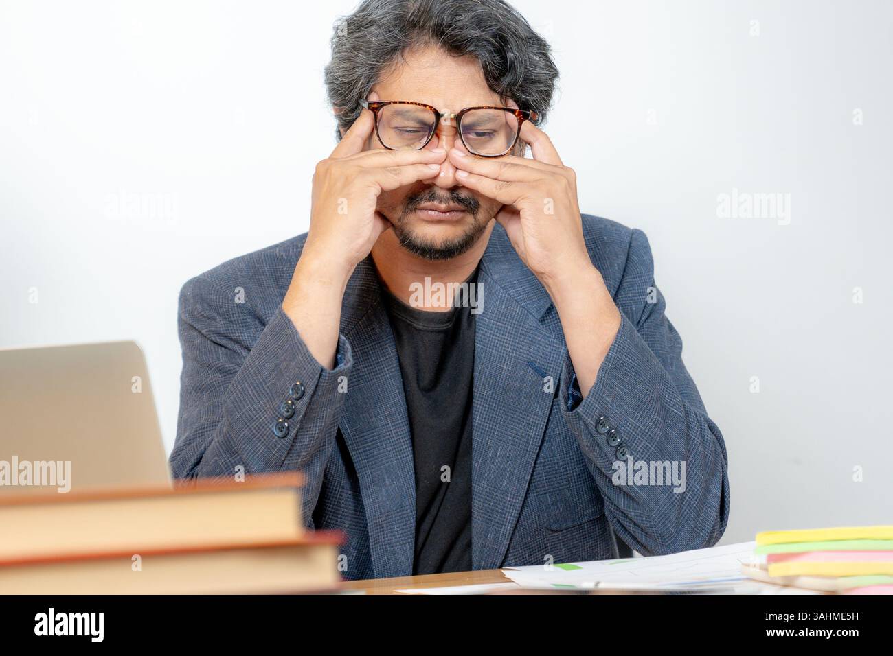 A young businessman staring at his computer screen for hours, rubbing ...